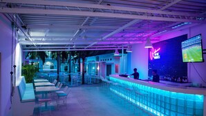 Área de bar moderna com luminária de neon, balcão e assentos.