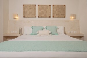 Cama bem arrumada com um cobertor azul claro, duas almofadas e cabeceira com painéis trançados.