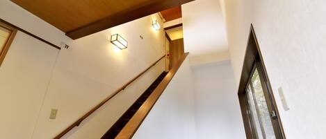 Escada com corrimãos de madeira e luminária moderna.