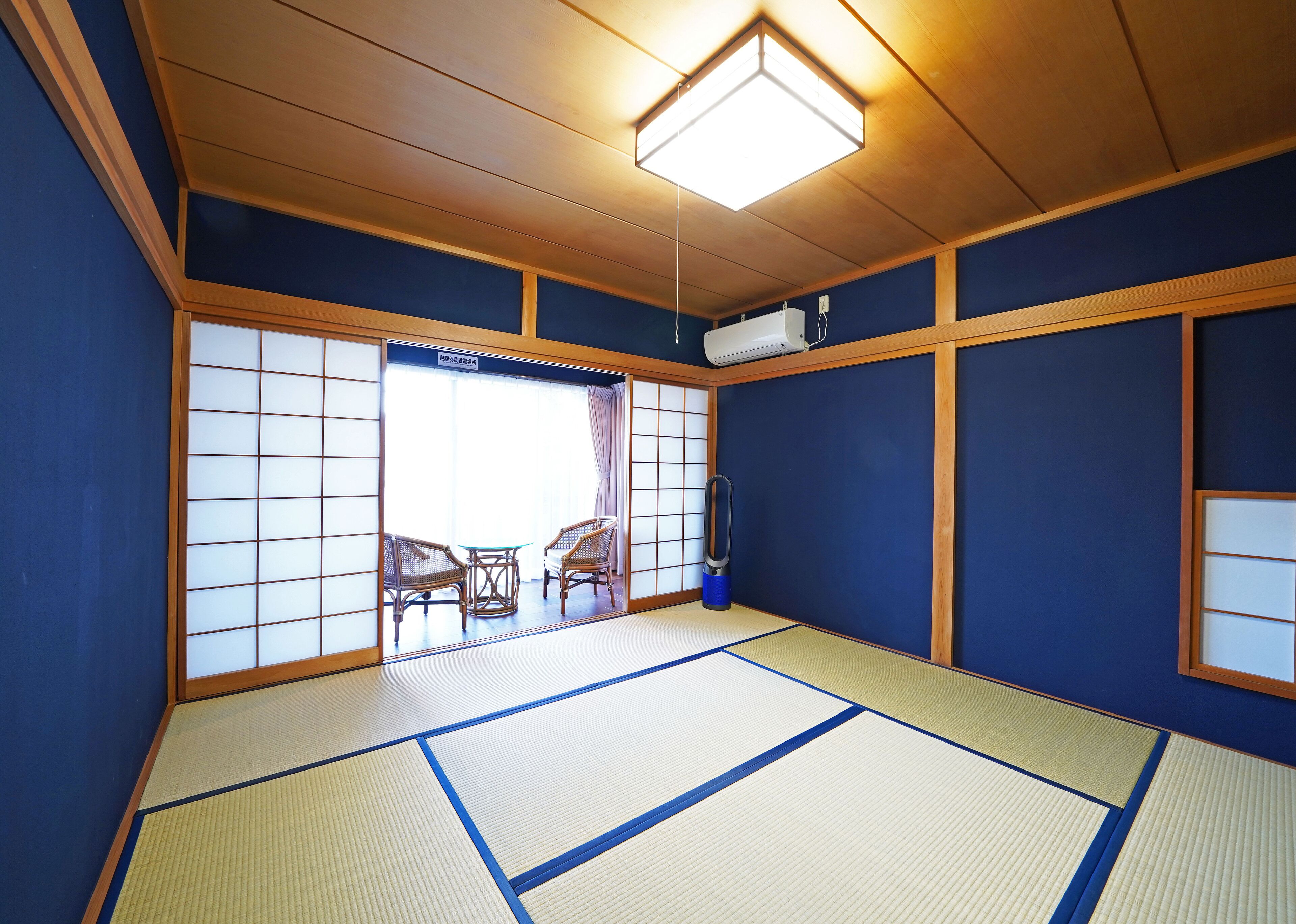 Um quarto japonês tradicional, com piso de tatame, portas deslizantes shoji e luminária no teto.