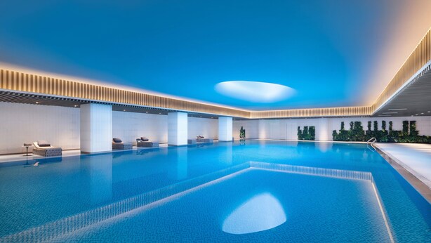 Piscina interior ampla com água cristalina, arquitetura moderna e áreas de estar.