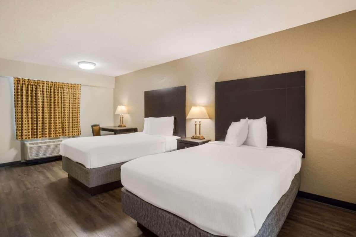 Quarto de hotel com duas camas, uma escrivaninha e uma cadeira.
