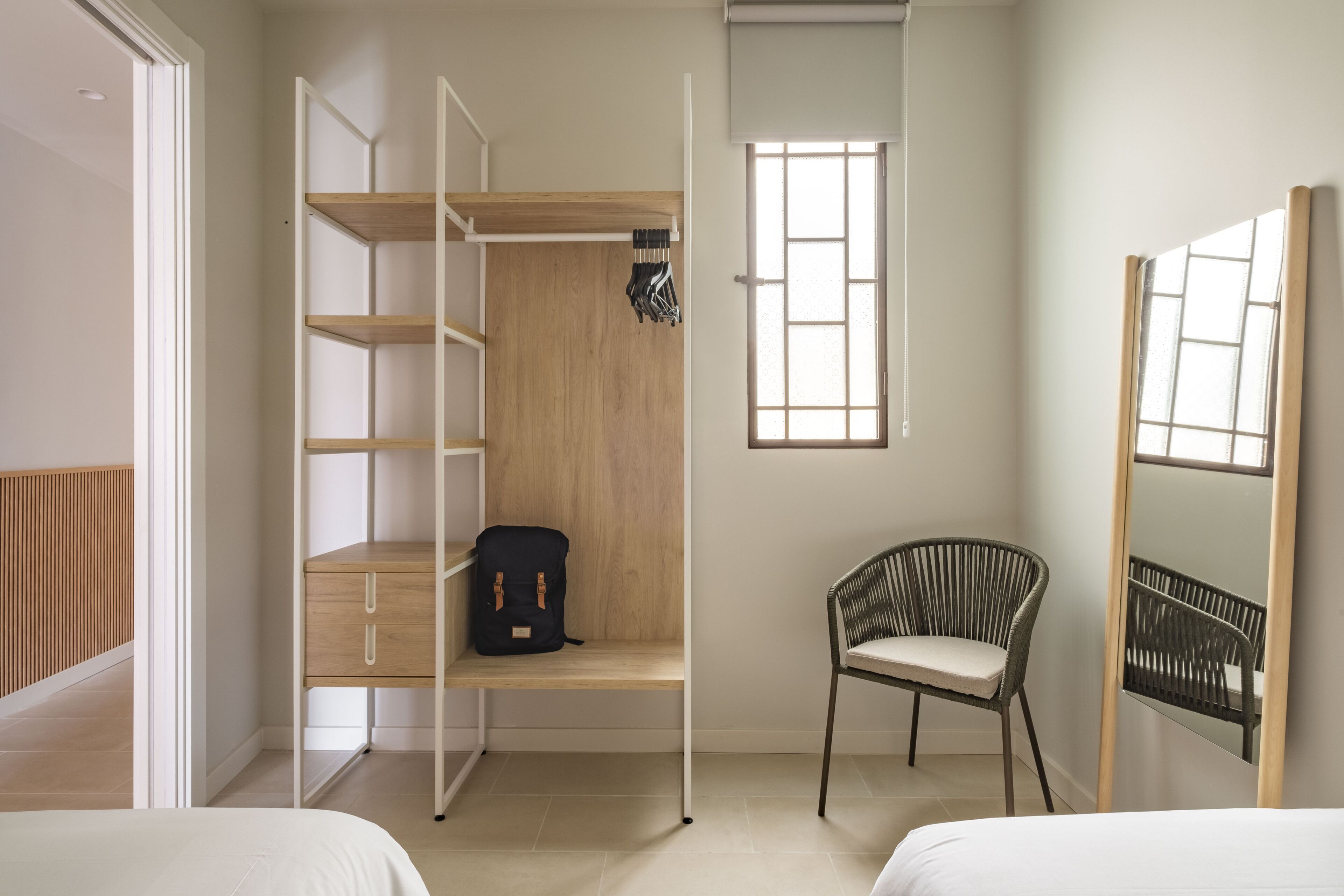 Quarto com cama, cadeira, guarda-roupa com prateleiras e janela.