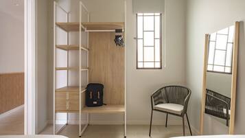 Quarto com cama, cadeira, guarda-roupa com prateleiras e janela.