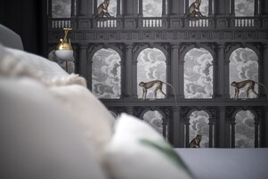 Um quarto com uma cama, um abajur e uma parede decorada com figuras de macacos.