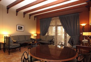 Um quarto aconchegante com uma mesa redonda de madeira, dois sofás e uma mesa de jantar.