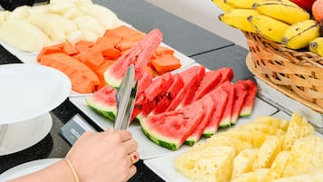 Uma tábua de frutas com melancia, abacaxi e bananas.