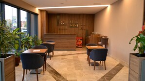 Um restaurante moderno com área de bar, disposição de mesas e plantas em vasos.