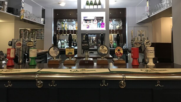 Zona de bar com várias torneiras e seleção de garrafas.