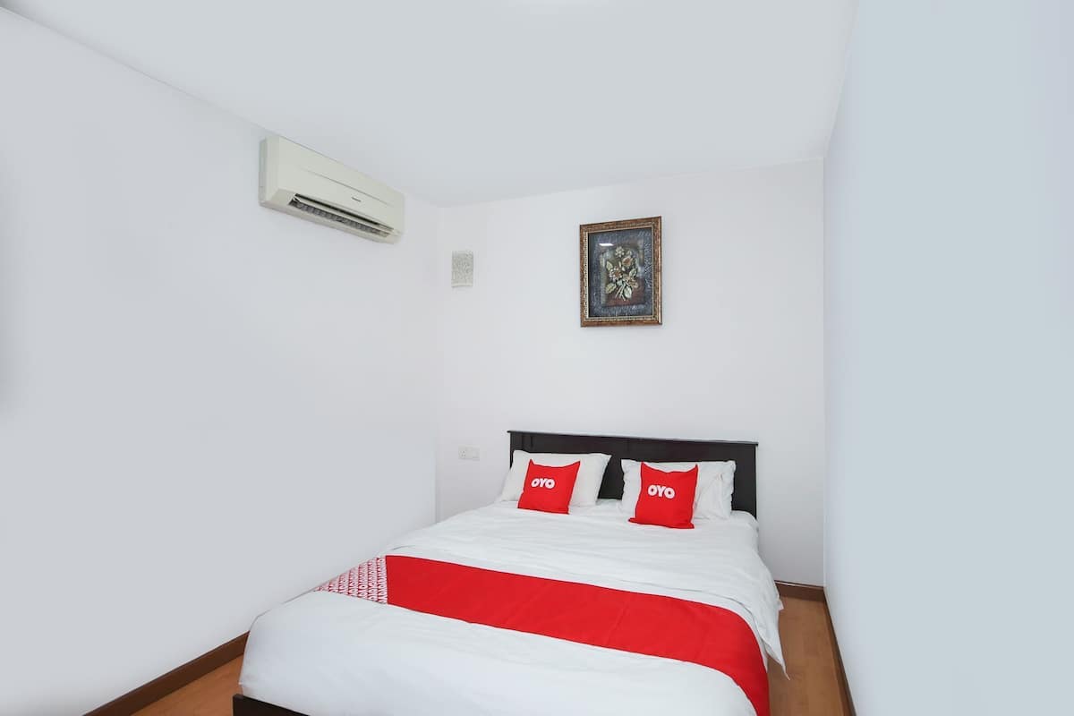 Quarto de hotel com cama, ar condicionado fixado na parede e um quadro emoldurado.