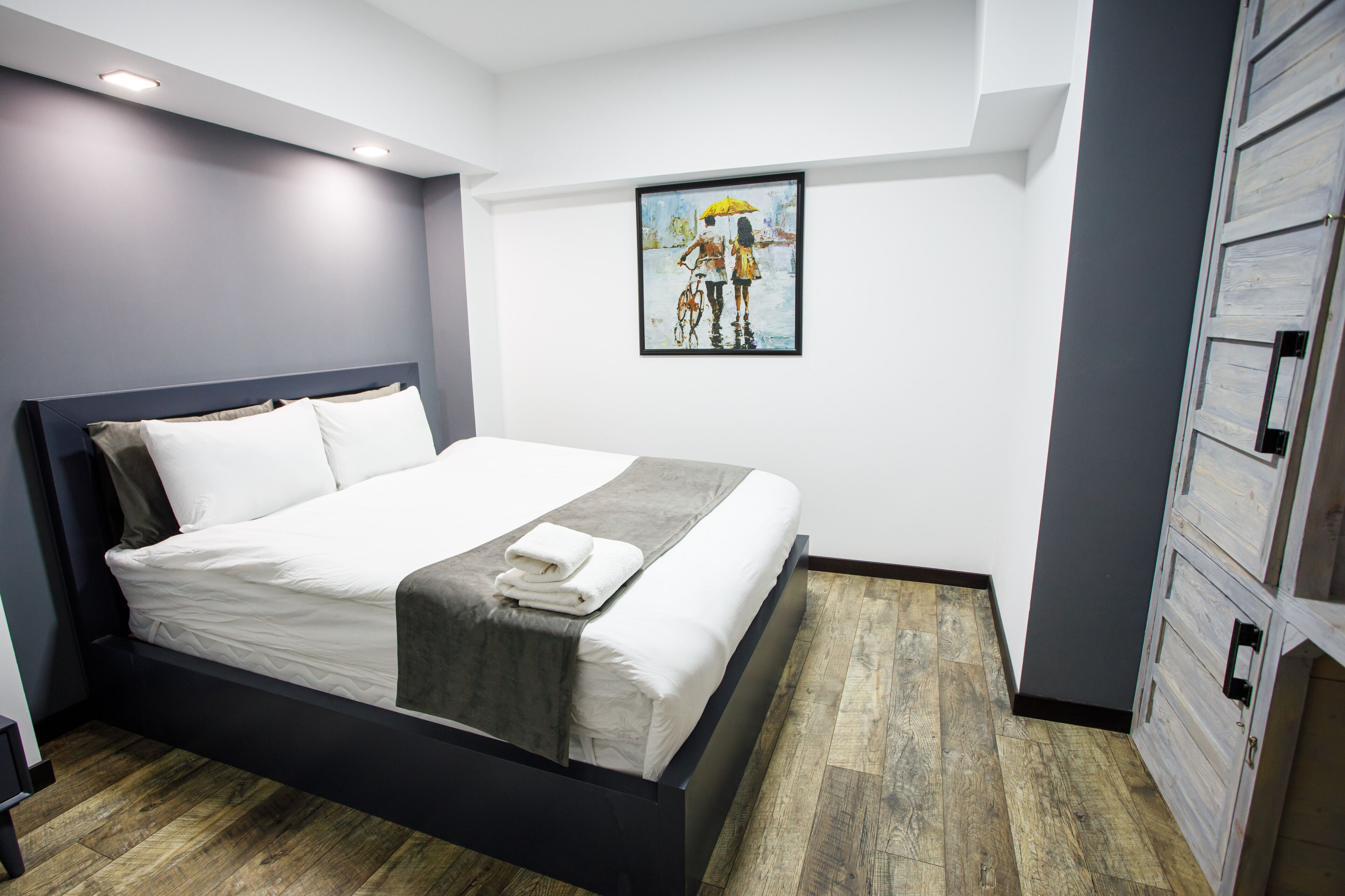 Quarto de hotel moderno com uma cama grande, um quadro na parede e um guarda-roupa.