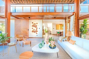 Uma sala de estar ampla com design moderno, com um sofá grande, uma mesa de centro e algumas cadeiras.