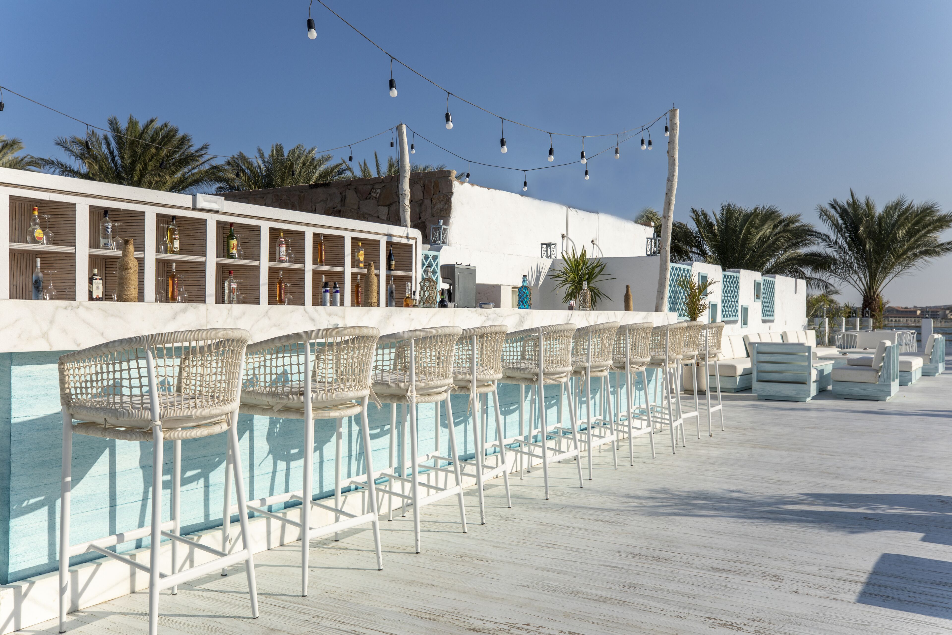 Uma área de bar à beira da piscina com cadeiras de vime e um balcão longo.
