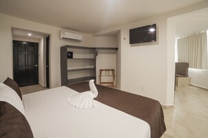 Quarto de hotel com cama, televisão, guarda-roupa e uma cadeira.