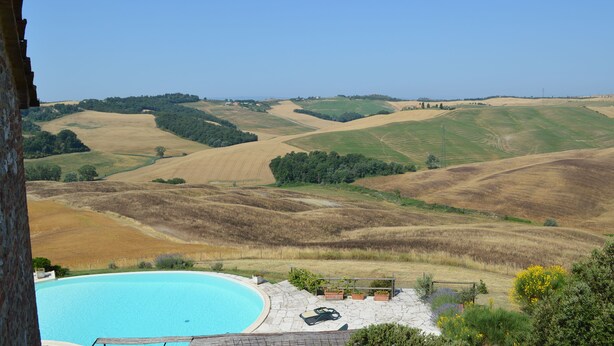 Área de piscina com vista para colinas ondulantes e céu claro.