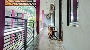 Um corredor com corrimão de metal, uma mesa de madeira e uma janela com vista para o verde.