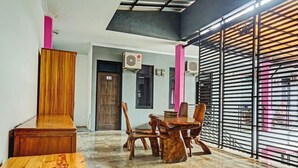 Uma área de refeições com mesa e cadeiras de madeira, aparelhos de ar condicionado e um guarda-corpo de metal.
