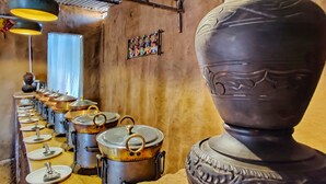 Um balcão comprido com várias panelas de metal e um vaso decorativo grande.