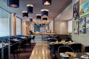 Uma sala de jantar moderna com mesas, cadeiras e um balcão com itens de café da manhã.
