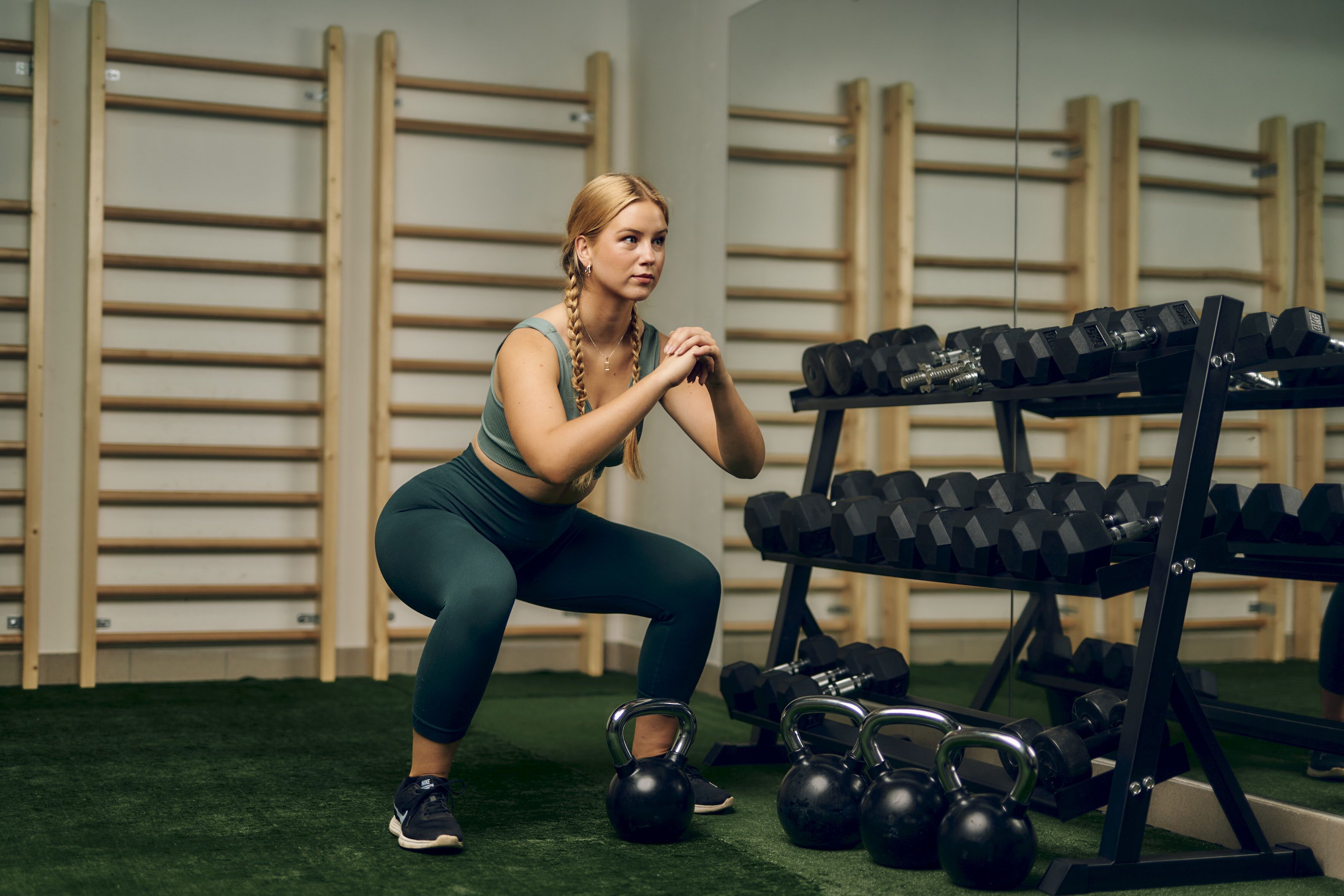 Uma academia com equipamentos de exercícios, incluindo kettlebells e halteres.