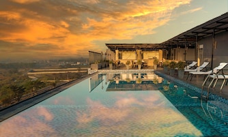 Piscina infinita no terraço com vista para a paisagem, área de bar e cadeiras de lounge.