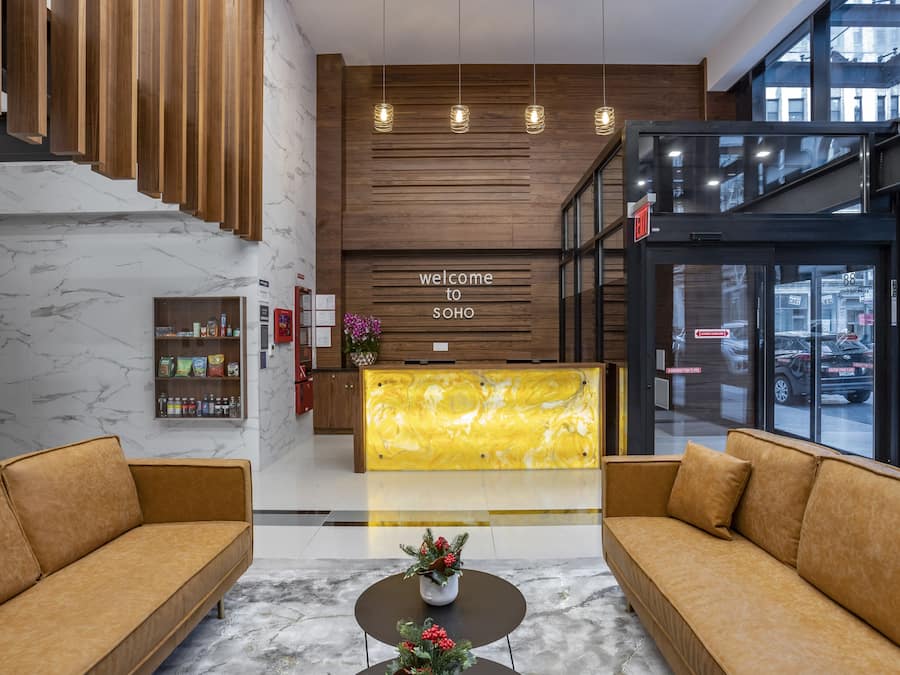 Um lobby moderno com balcão de recepção, sofás, piso de mármore e vista para a rua através de grandes janelas.