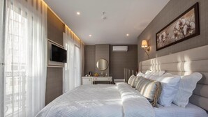Quarto de hotel moderno com uma cama grande, mesa de cabeceira, televisão e um quadro na parede.