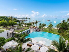 Um resort com piscina, área de estar e vista para o mar com barcos.