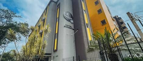 Um hotel com design moderno, destacando uma estrutura vertical imponente e fachada amarela.