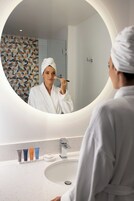Casa de banho moderna com um espelho grande, lavatório com artigos de higiene e parede estampada.