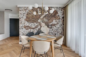 Uma área de refeições com uma mesa redonda, quatro cadeiras e um mural na parede.