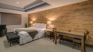 Quarto com cama, mesas de cabeceira, escrivaninha e uma cadeira.