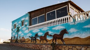 Um edifício com um mural de cavalos e palmeiras na fachada.