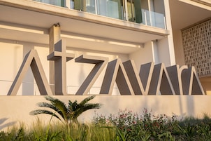 Fachada de edifício moderna com padrões geométricos e uma palmeira em primeiro plano.