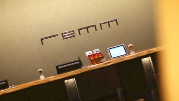 Uma mesa de recepção com uma placa com a inscrição "FEMM" e um monitor de computador.