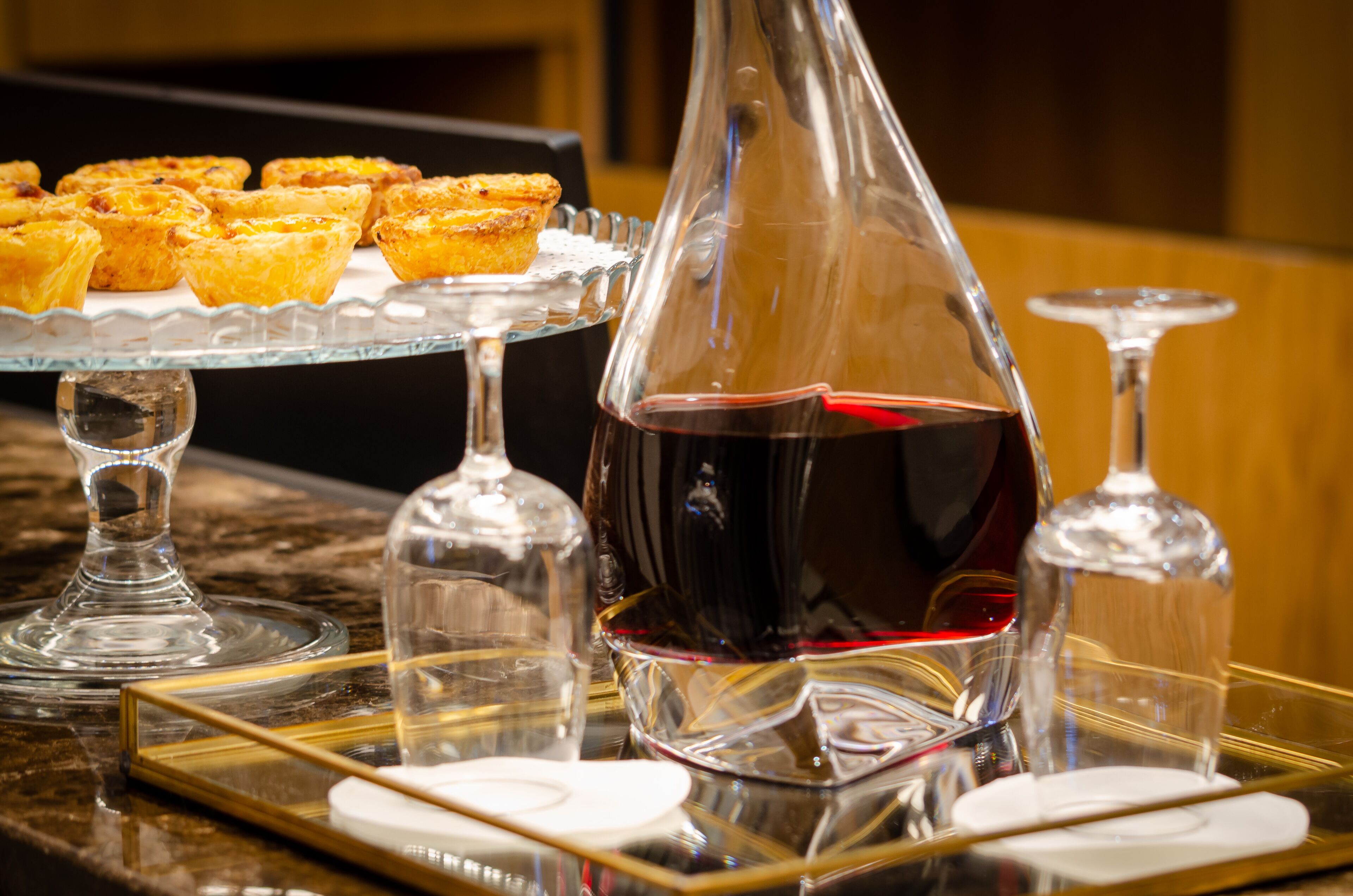 Uma vitrine de vidro com doces e uma garrafa de vinho.