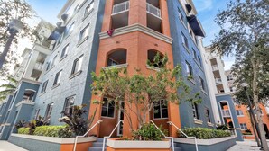Um edifício residencial com vários andares, varandas, um pátio central com uma árvore e um hidrante.