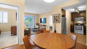 Uma cozinha moderna com armários de madeira escura, eletrodomésticos de aço inoxidável e uma grande mesa de jantar de madeira.