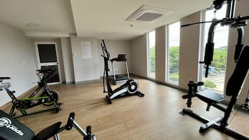 Uma academia com aparelhos de cardio, equipamentos de musculação e um banco.