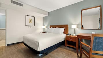 Quarto de hotel com uma cama, mesas de cabeceira, uma escrivaninha e uma cadeira.