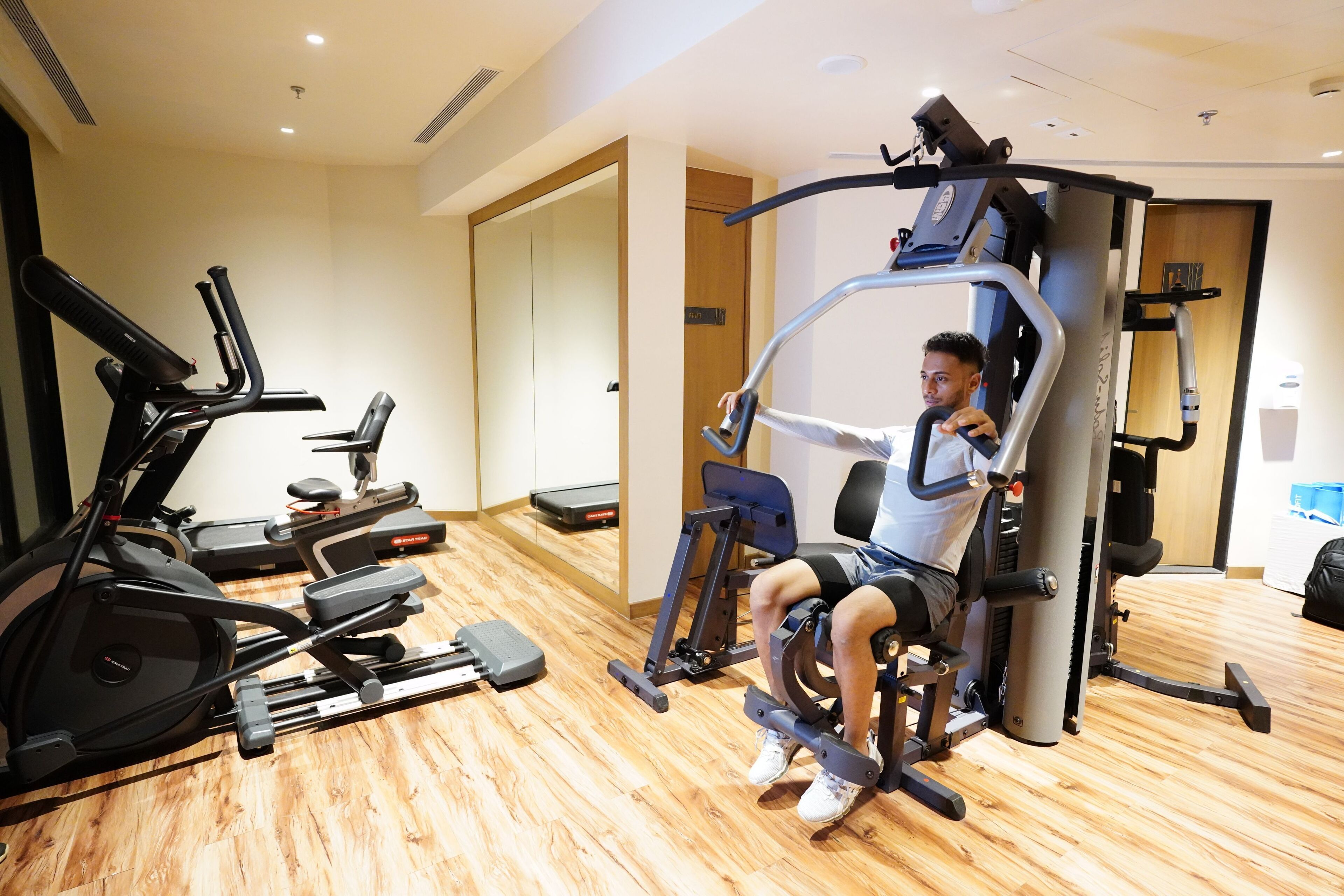 Uma academia com equipamentos de ginástica, incluindo bicicleta ergométrica, elíptico e aparelhos de musculação.