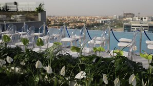 Uma área de piscina no terraço, com cadeiras confortáveis e vista para o horizonte urbano.