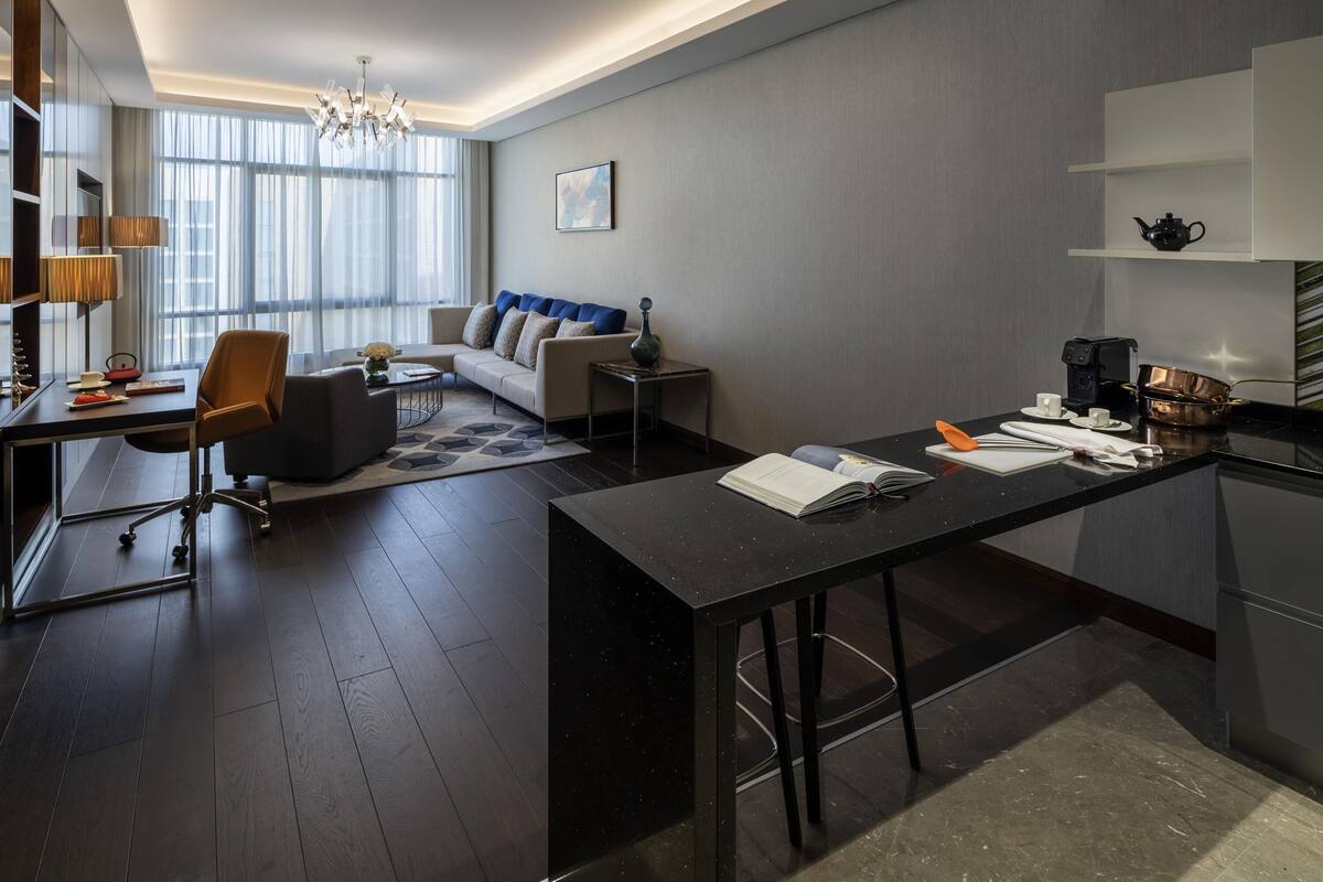 Quarto de hotel moderno com área de estar, mesa de jantar e cozinha.