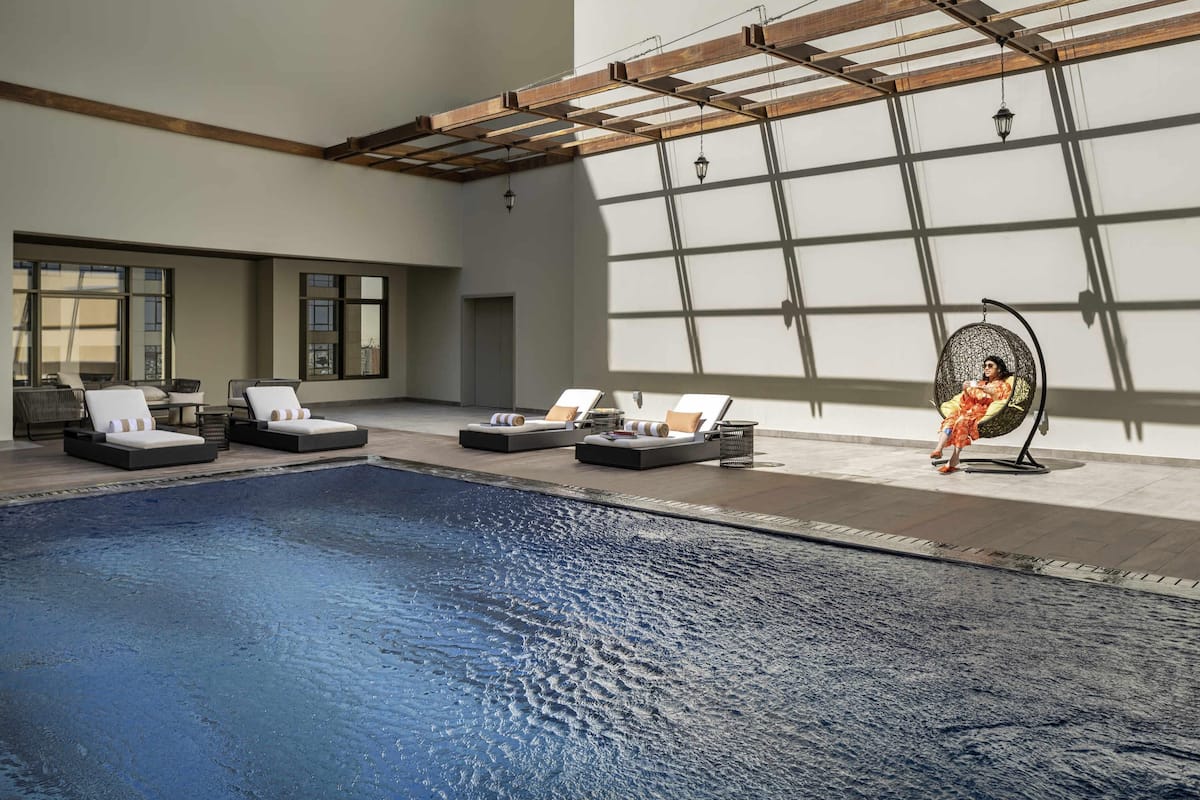 Uma piscina interna moderna com espreguiçadeiras e uma cadeira suspensa.