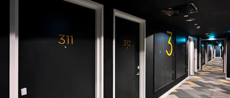 Corredor de hotel com portas numeradas 311, 312 e 313.