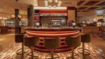 Uma área de bar com balcão curvo, banquetas e diversas garrafas de bebidas.