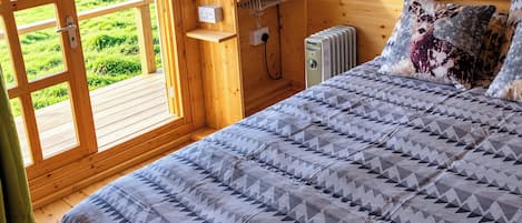 Quarto com cama, micro-ondas, aquecedor e vista para um campo verde.
