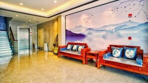 Um hall com piso de mármore, escada e um mural na parede.