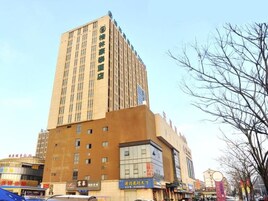 Um hotel alto com vários andares e uma placa grande na lateral.