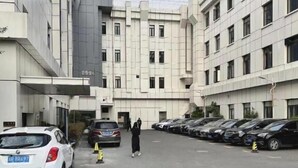 Um estacionamento com vários carros e uma pessoa caminhando.